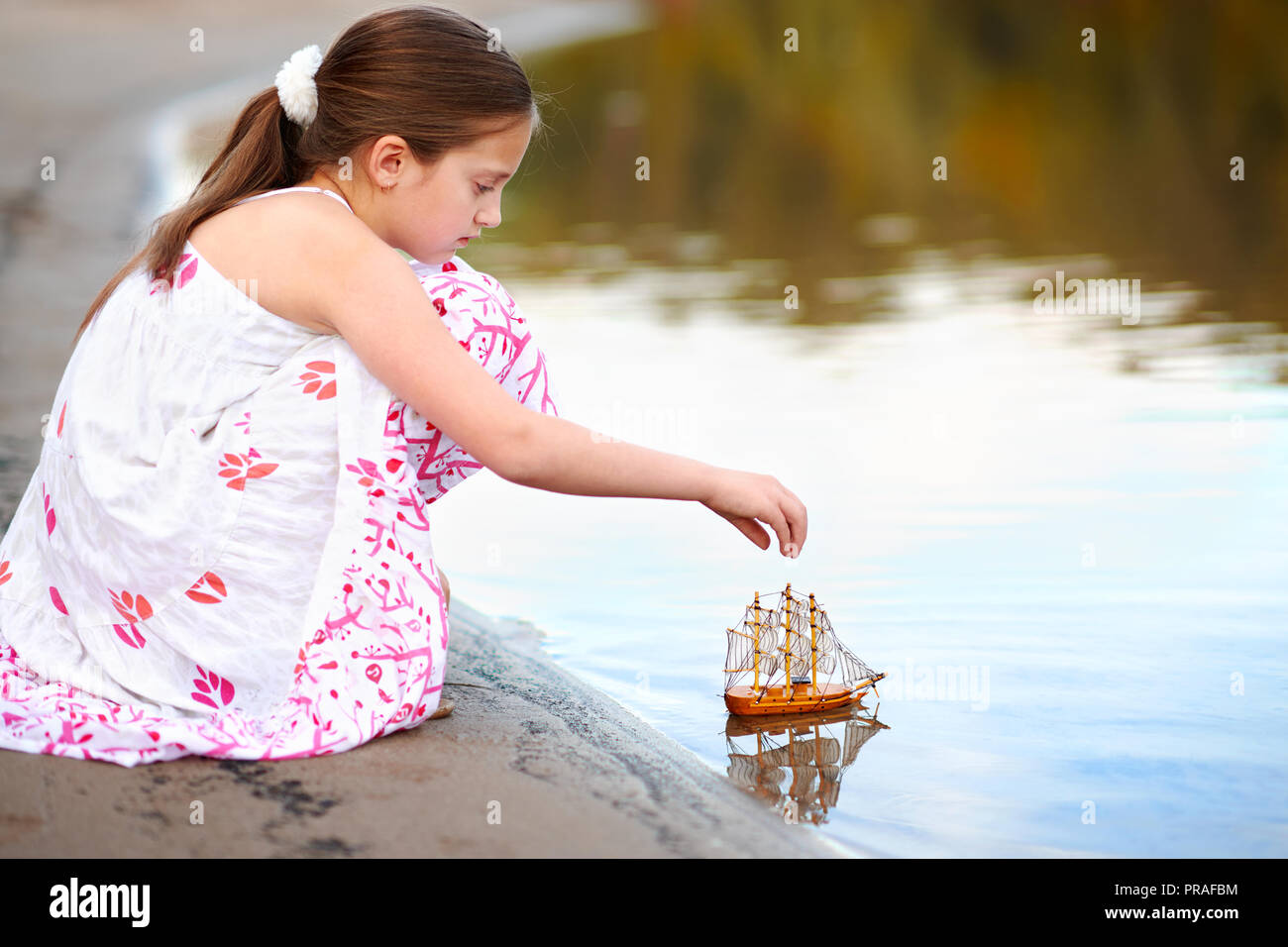 girl child playing with a toy sailing ship by the river Stock Photo - Alamy