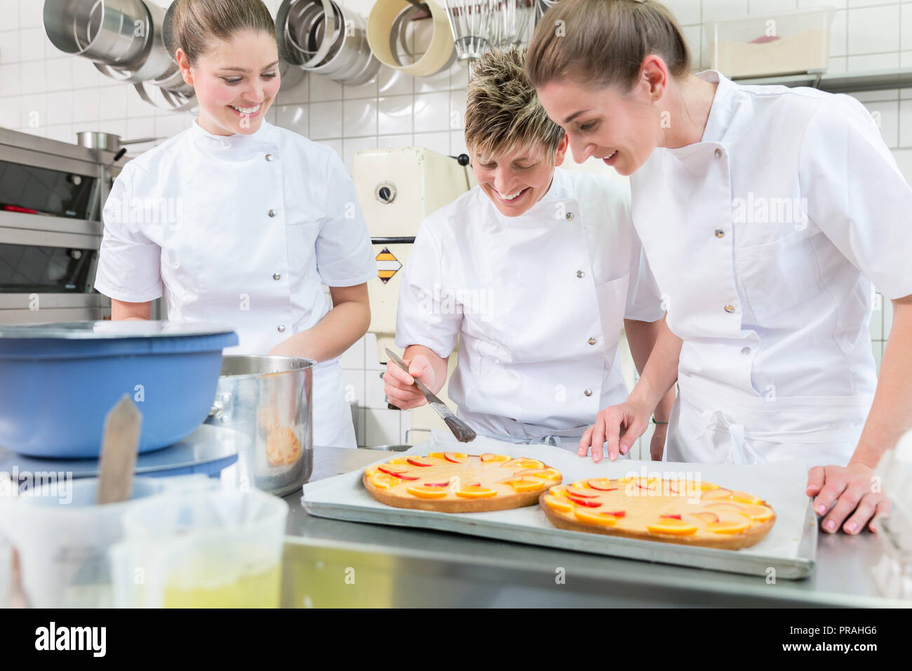Women putting fruit on cakes in pastry bakery Stock Photo - Alamy
