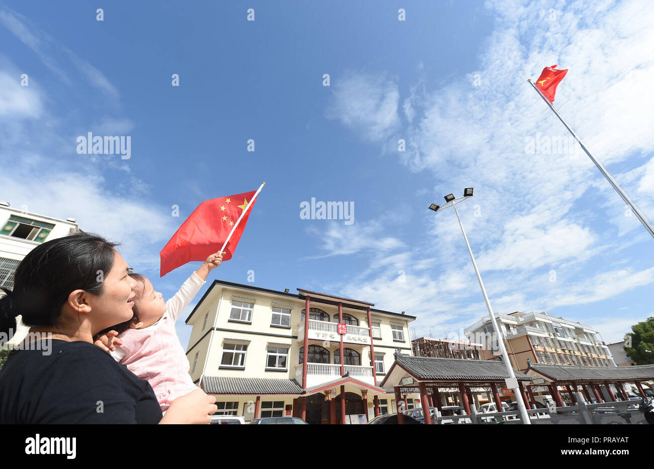 Yiwu. 1st Oct, 2018. A mother and her child view a national flag ...