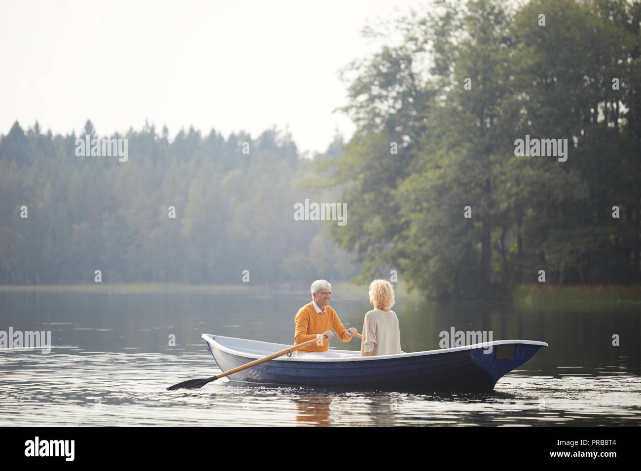 Excited handsome senior boyfriend in yellow sweater sitting on boat ...