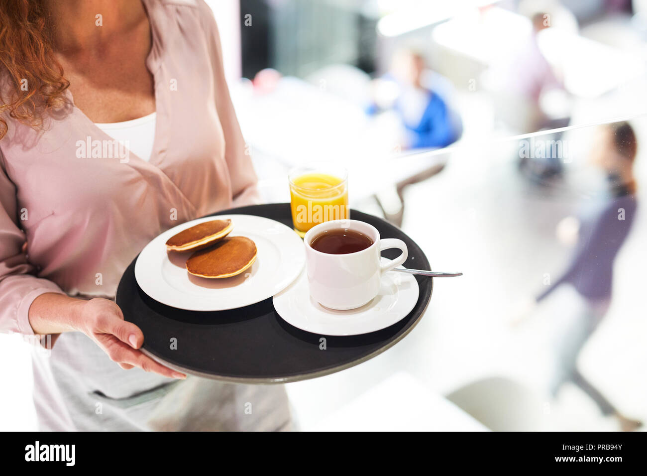 Close-up of unrecognizable waitress carrying tray with breakfast ...