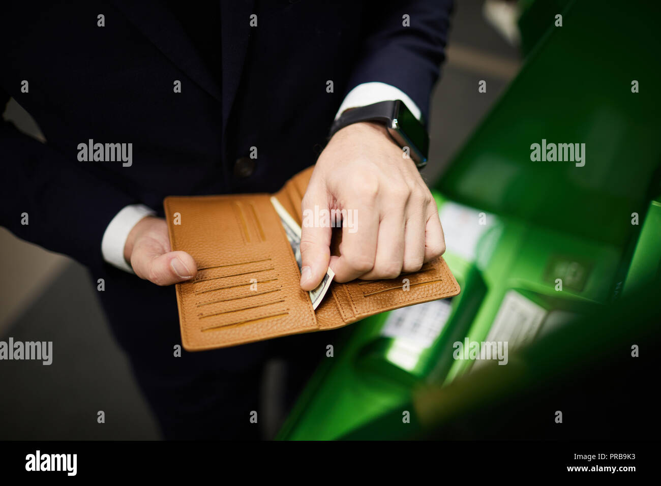 Hands of businessman putting banknotes into brown leather wallet after ...