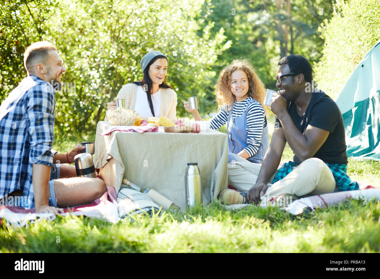 Four cheerful intercultural friends sitting around selfmade table in ...