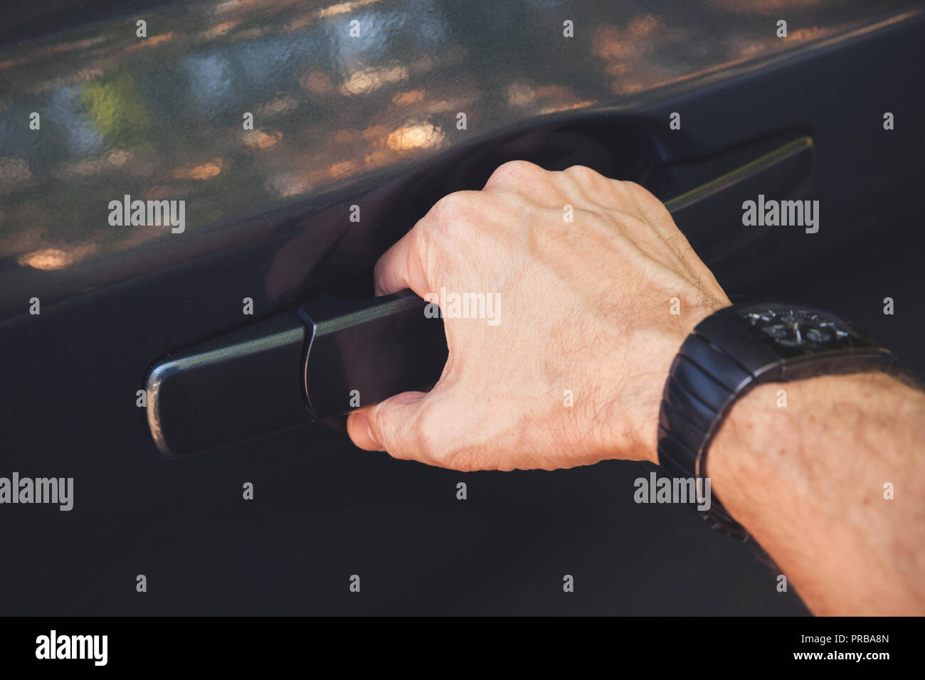Strong male hand with wrist watch opens car door, closeup photo with ...