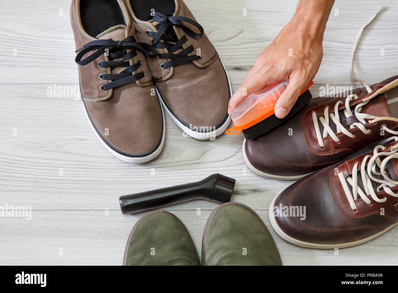 Man cleaning and polishing leather shoes with brush on wooden ...