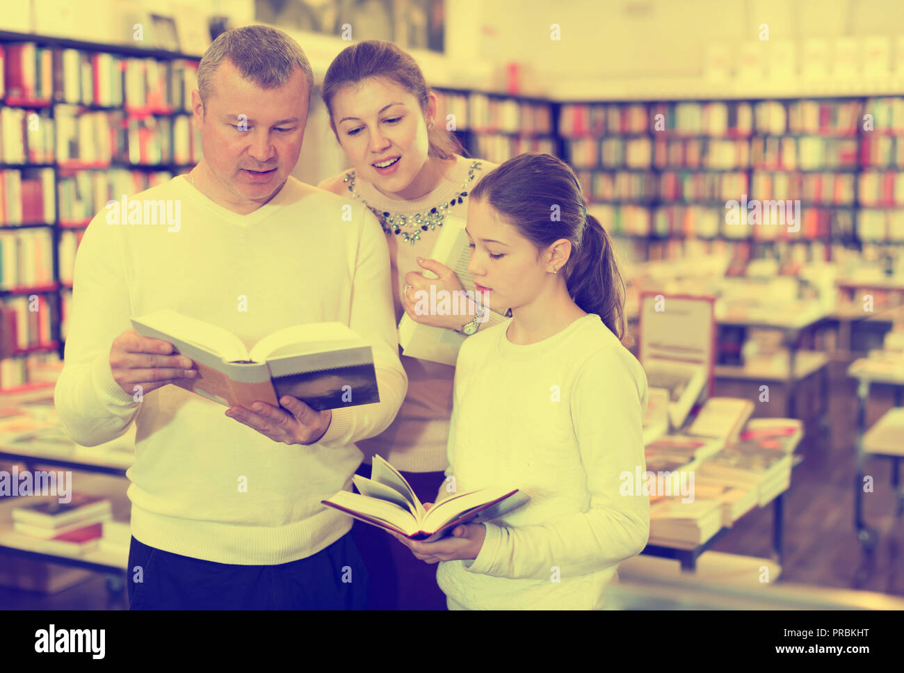 Adult family with preteen daughter reading interesting books in ...