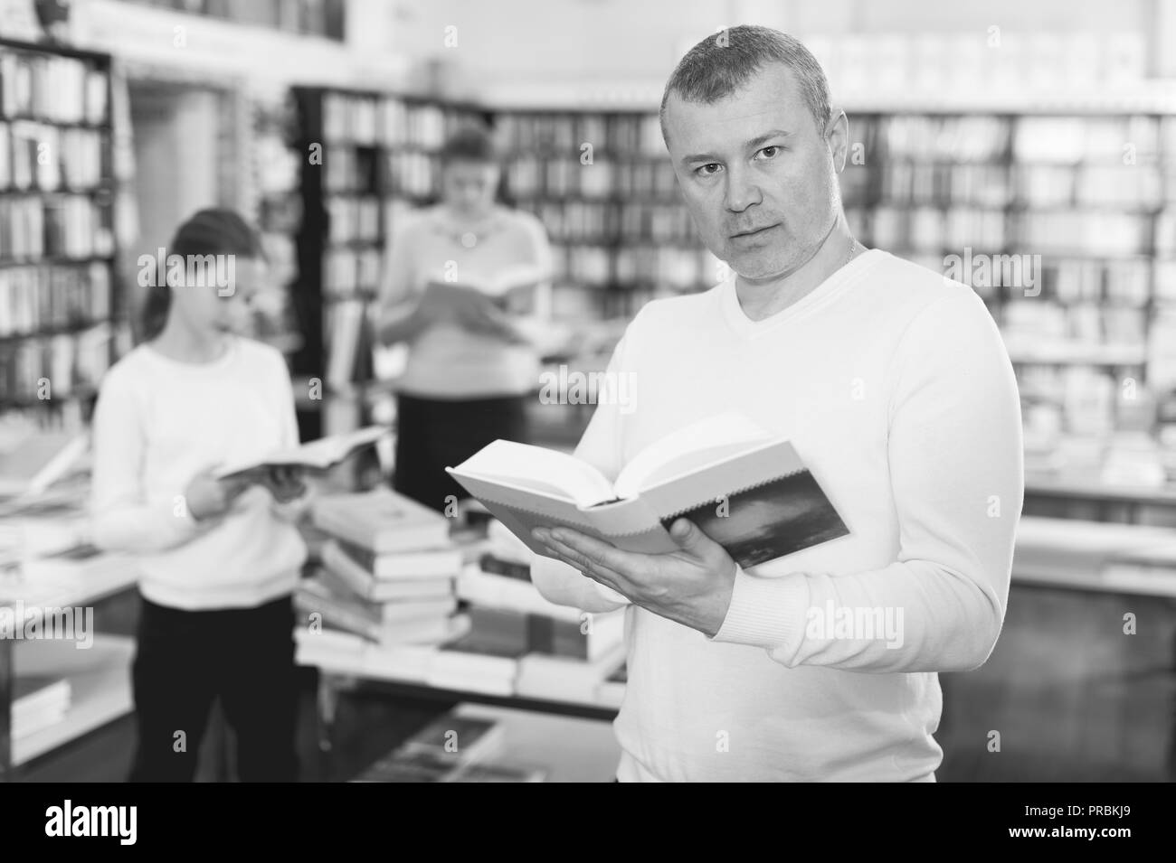 Positive man reading interesting books in bookstore Stock Photo - Alamy