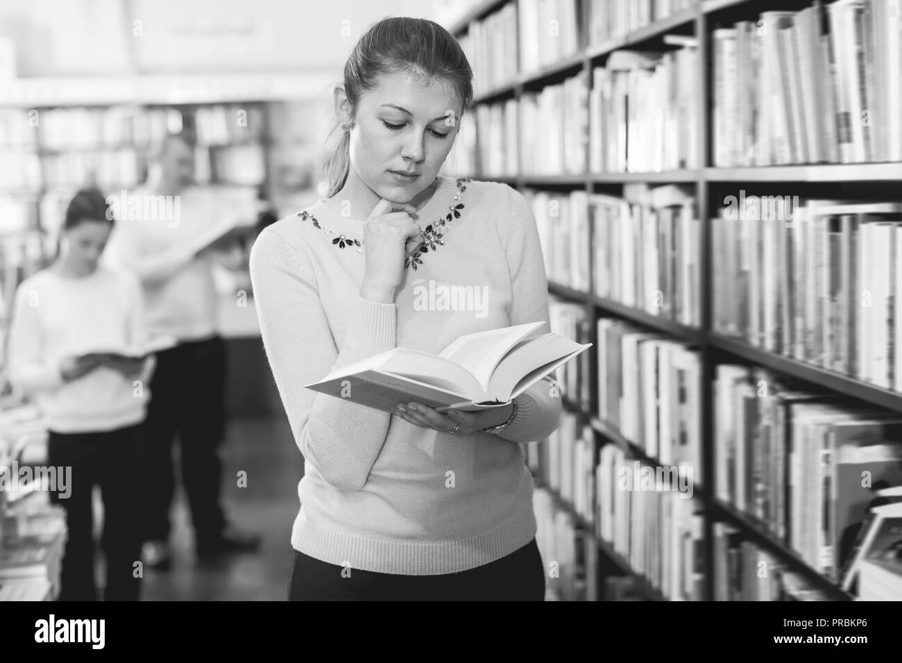 Portrait of pensive adult woman standing with open book in modern ...