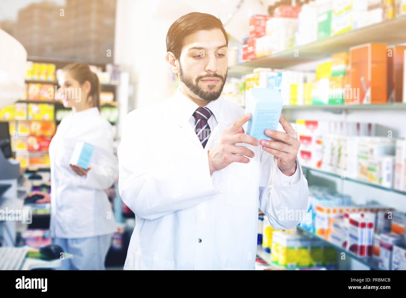 Portrait of adult man pharmacist who is standing with medicine on his ...