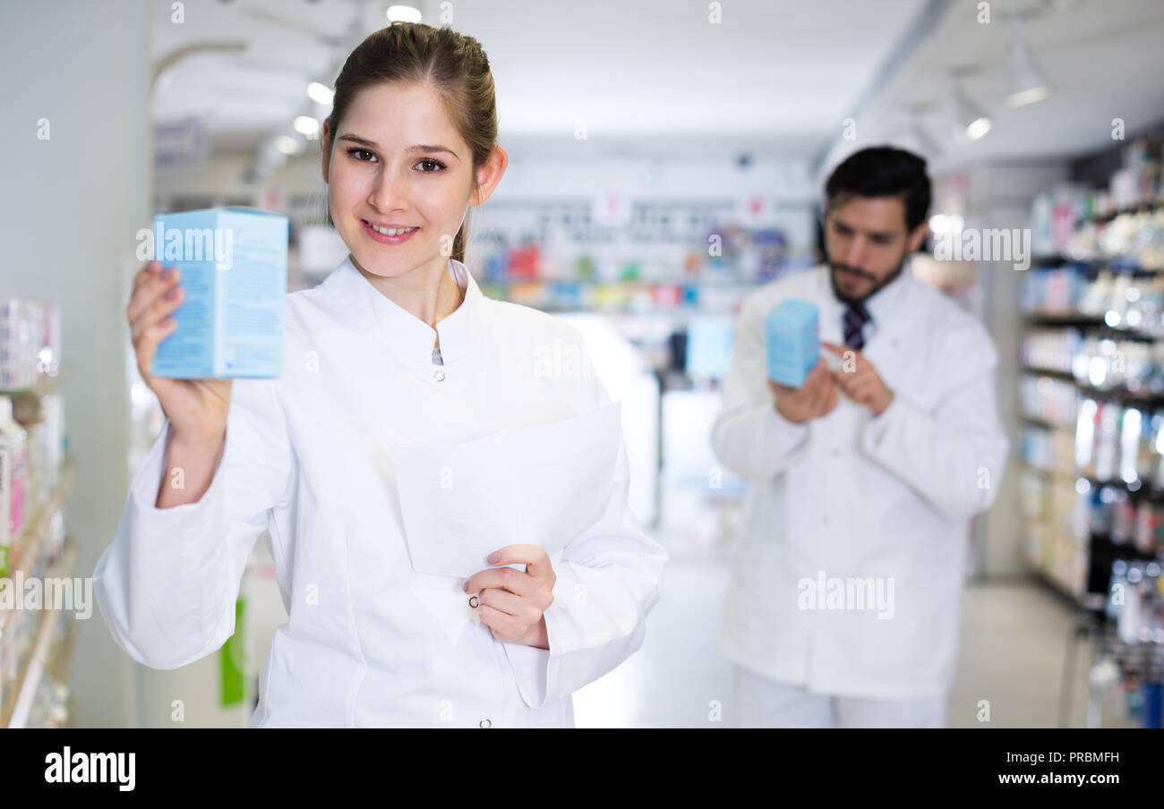 Portrait of nice female specialist who is holding medicines near ...