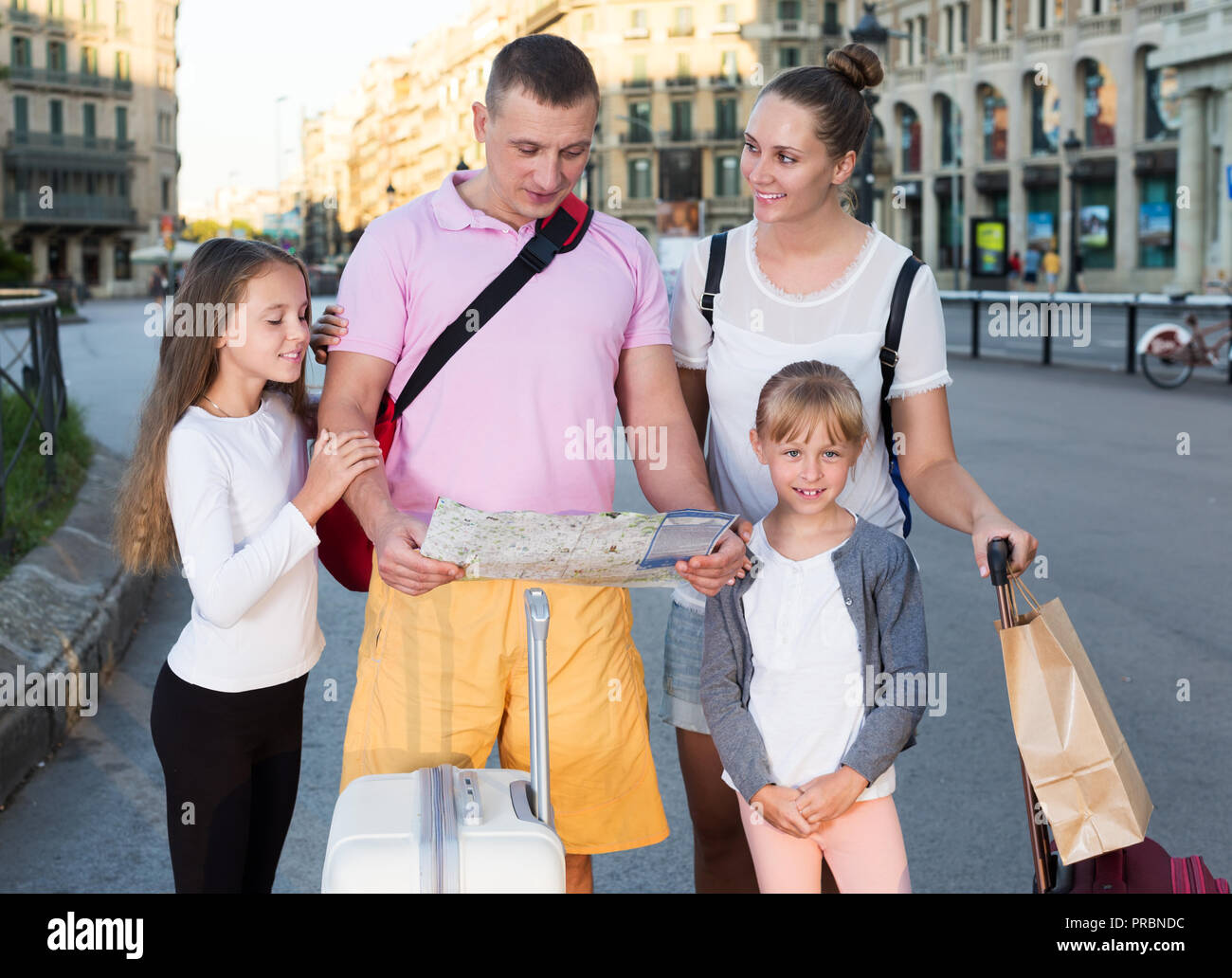 Cheerful family of tourists with two kids looking for destination with ...