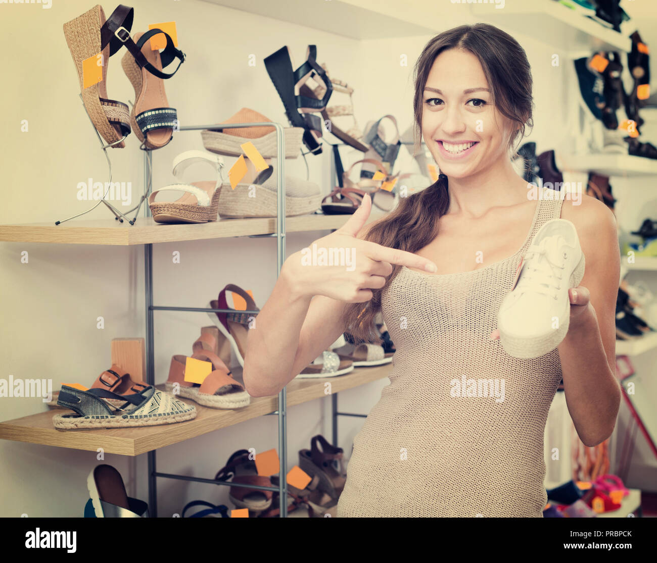 Beautiful young female customer showing desired shoe in boutique Stock ...