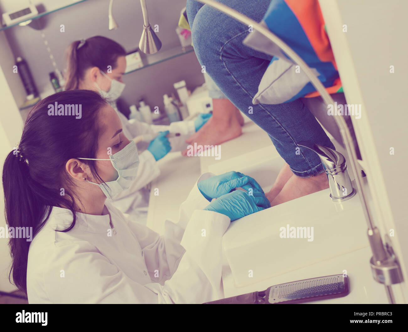 Nail master performing pedicure and foot reflexology in beauty salon ...