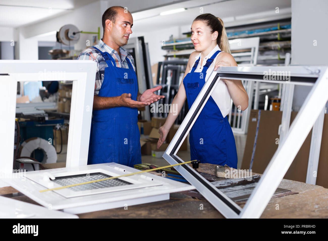 Man worker helping girl in work of assembling plastic windows at ...