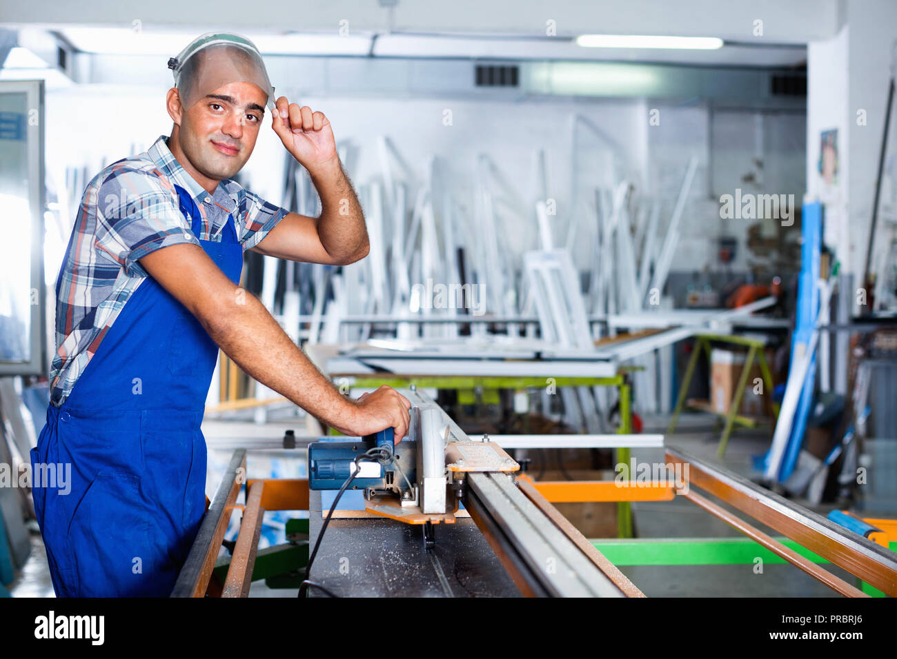 Confident diligent smiling workman ready to working on circular saw in ...