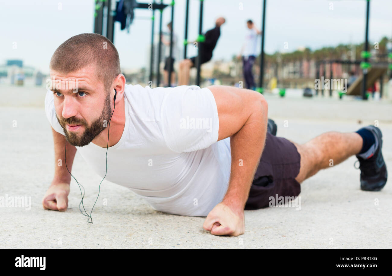 Strong man performs push-ups on an outdoor sports field Stock Photo - Alamy