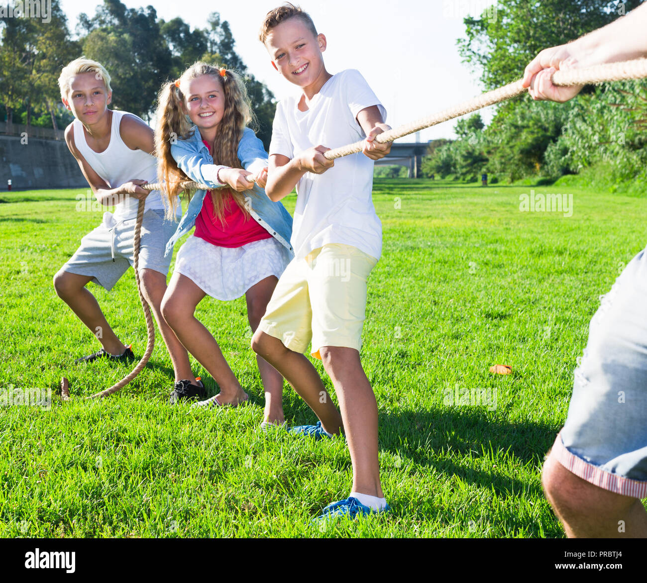 Children playing tug of war during joint games outdoors on sunny day ...
