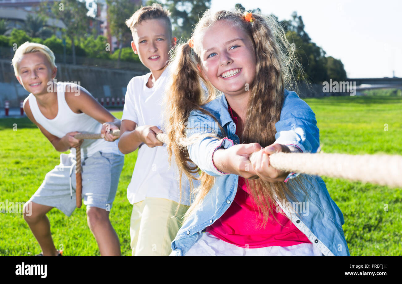 Three happy kids playing active games in summer park, tugging war Stock ...