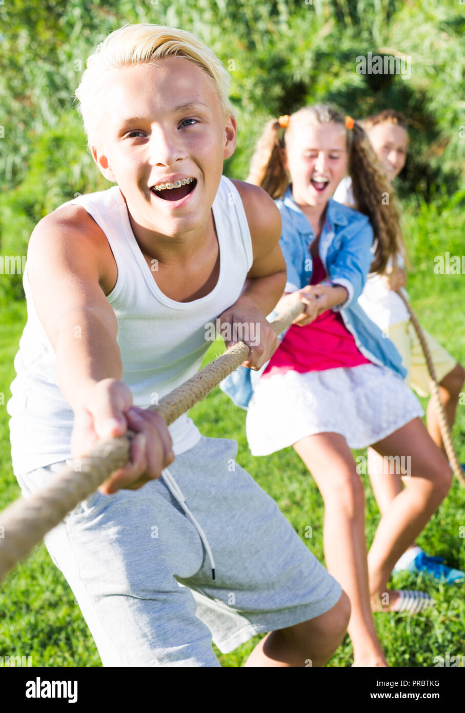 Children playing tug of war during joint games outdoors on sunny day ...