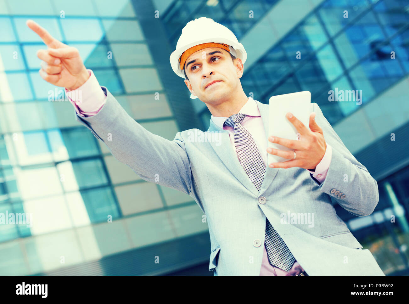 Portrait of manager of plant giving instructions and pointing with his ...