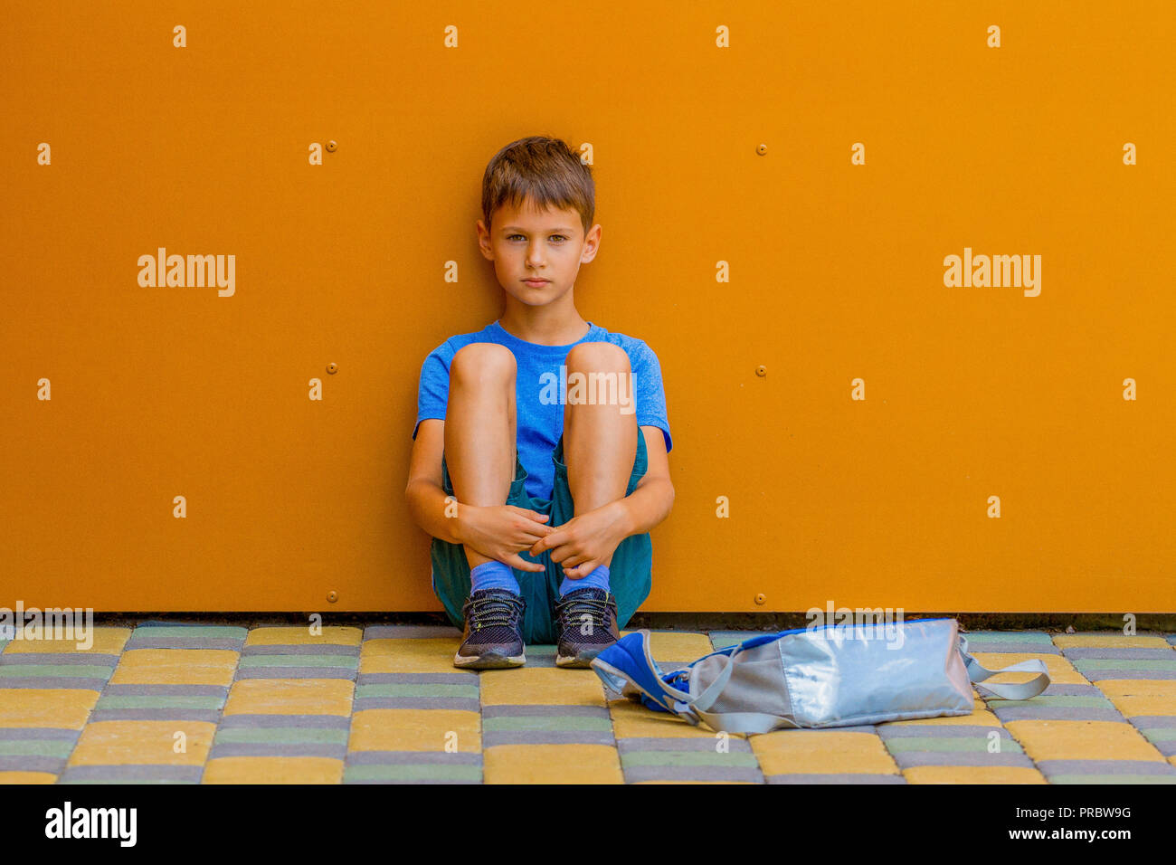 Sad alone boy sitting near colorful wall outdoors Stock Photo - Alamy