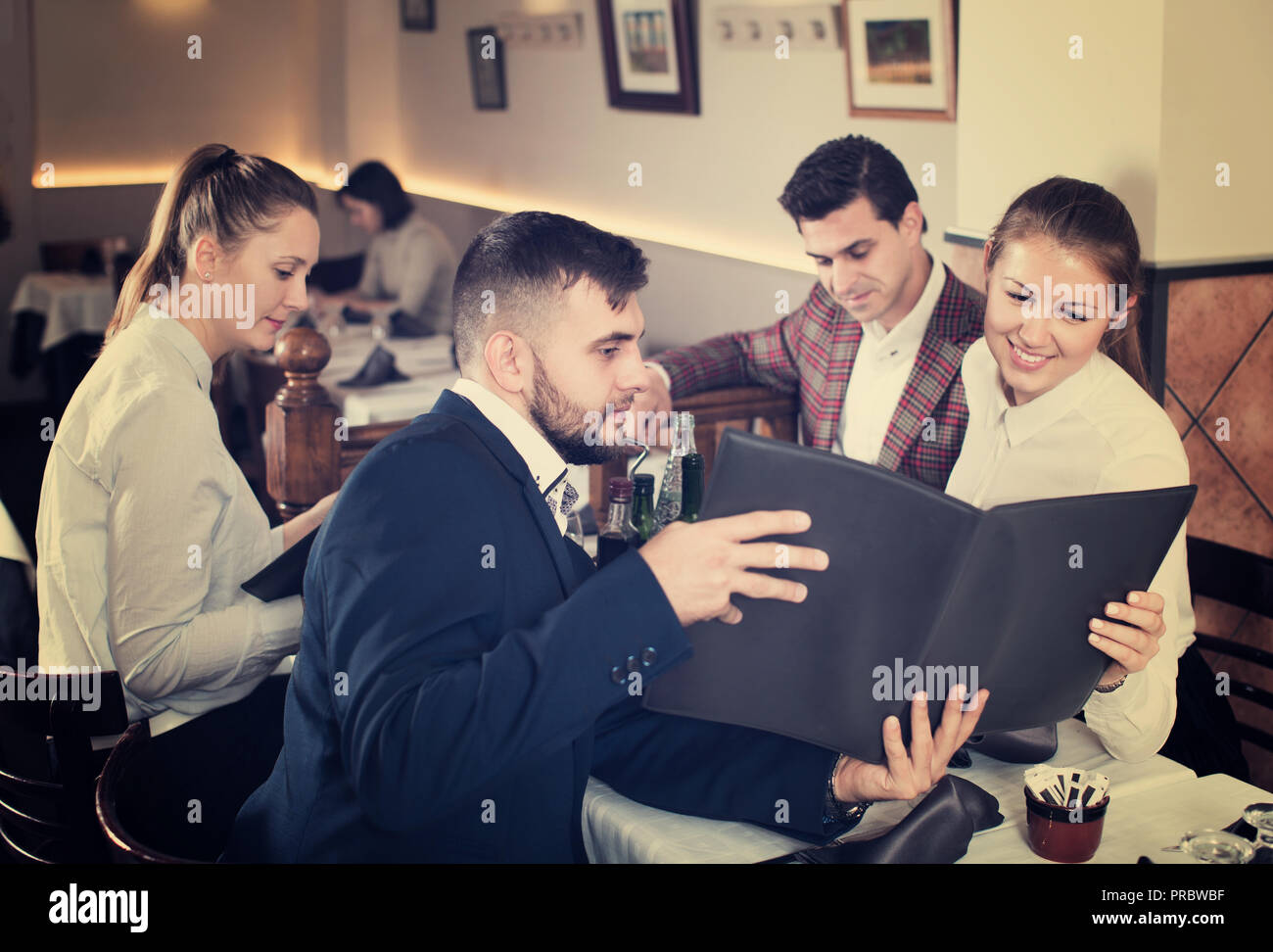 Group of cheerful friends enjoying meeting at restaurant, choosing meal ...