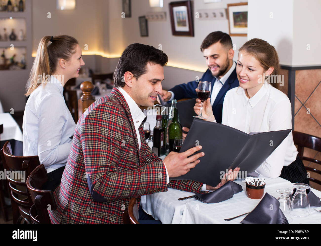 Group of positive friends enjoying dinner at restaurant, choosing meal ...