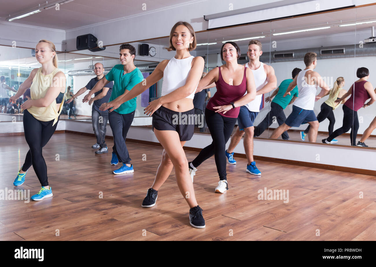 Young cheerful people dancing zumba elements in dancing hall Stock ...