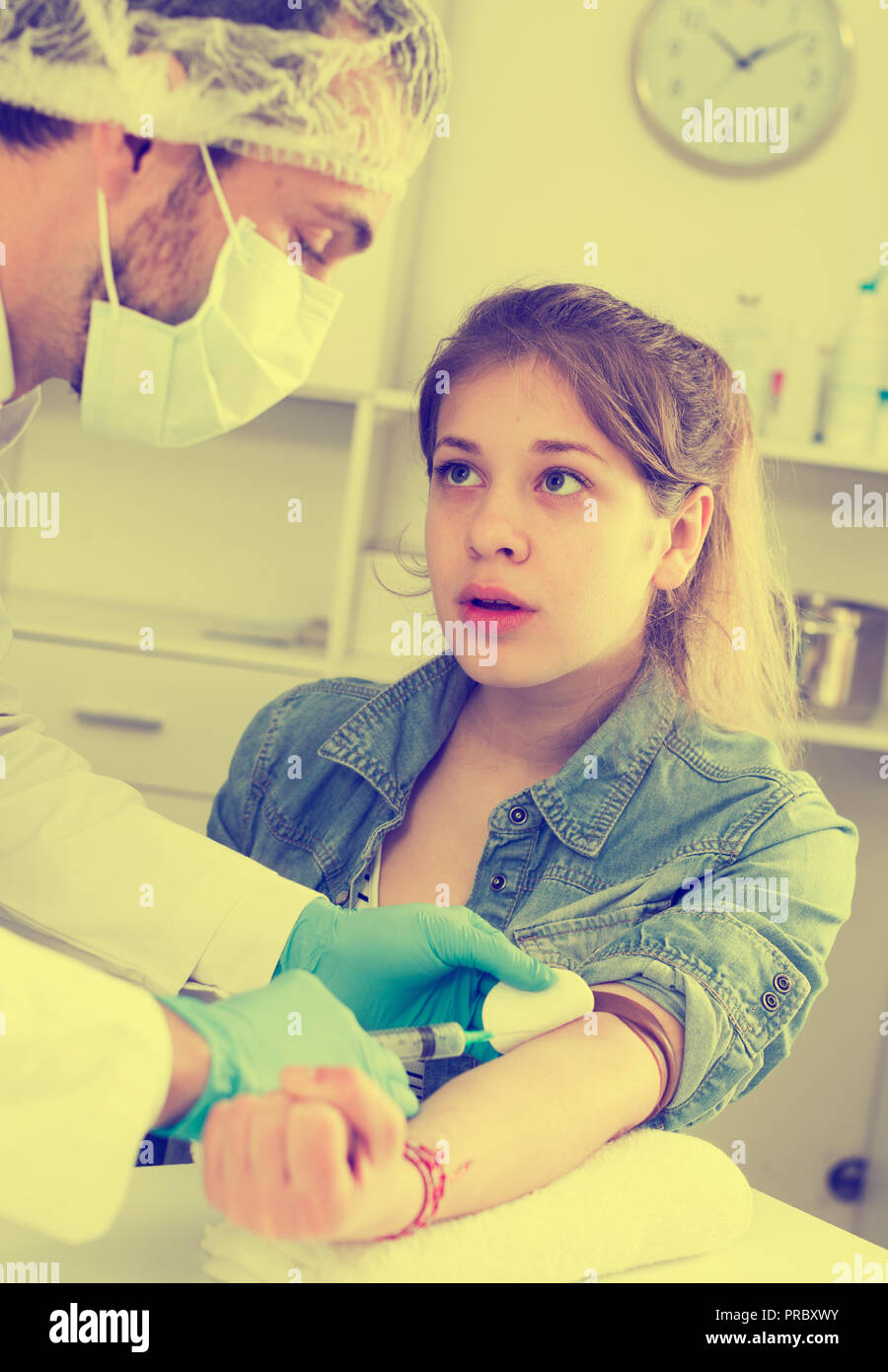 Male doctor using syringe to make injection to young patient in ...