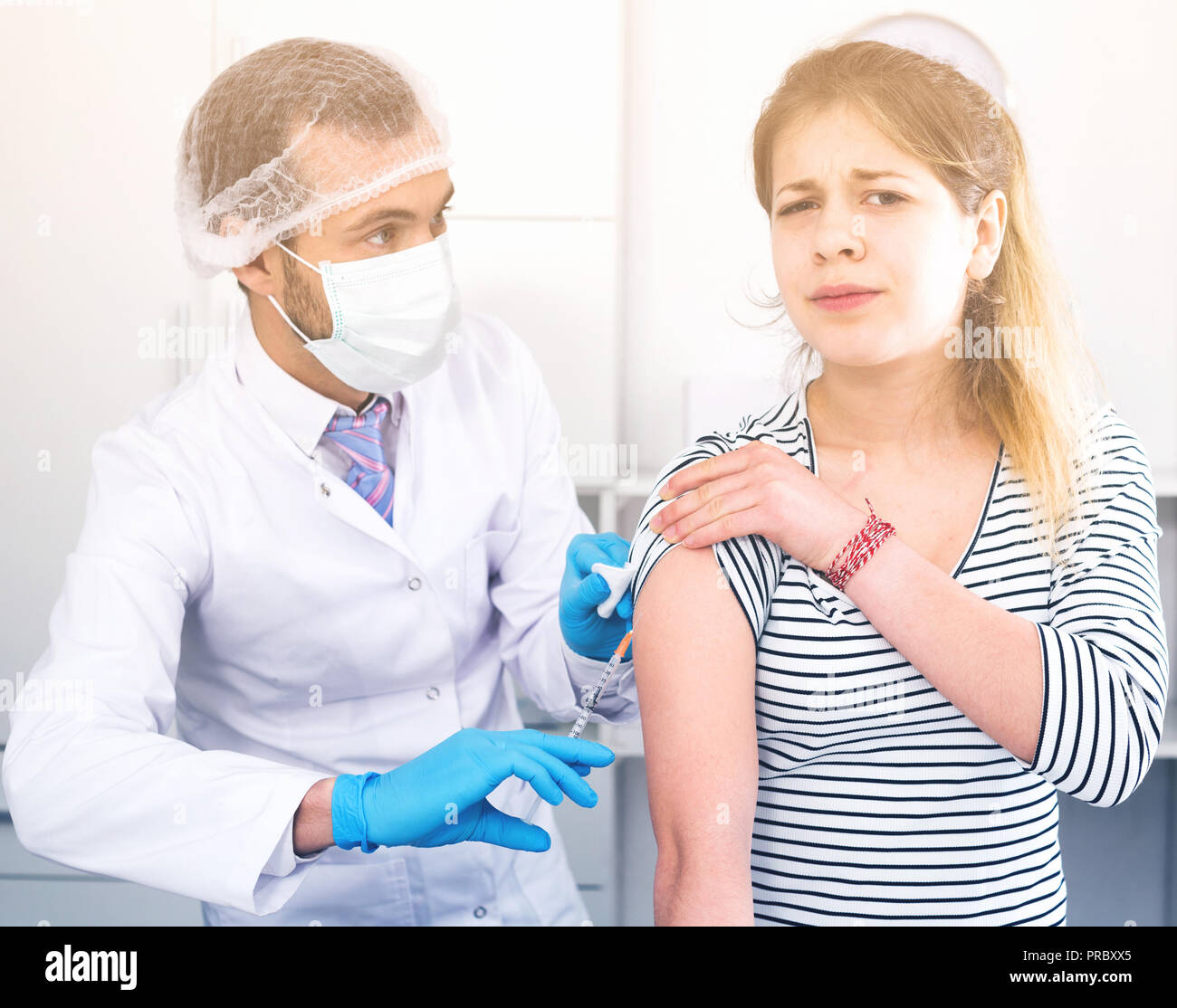 Male doctor using syringe to make injection of vaccine to young patient ...