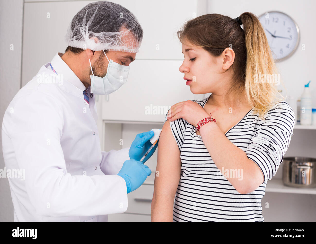 Male doctor using syringe to make injection of vaccine to young patient ...
