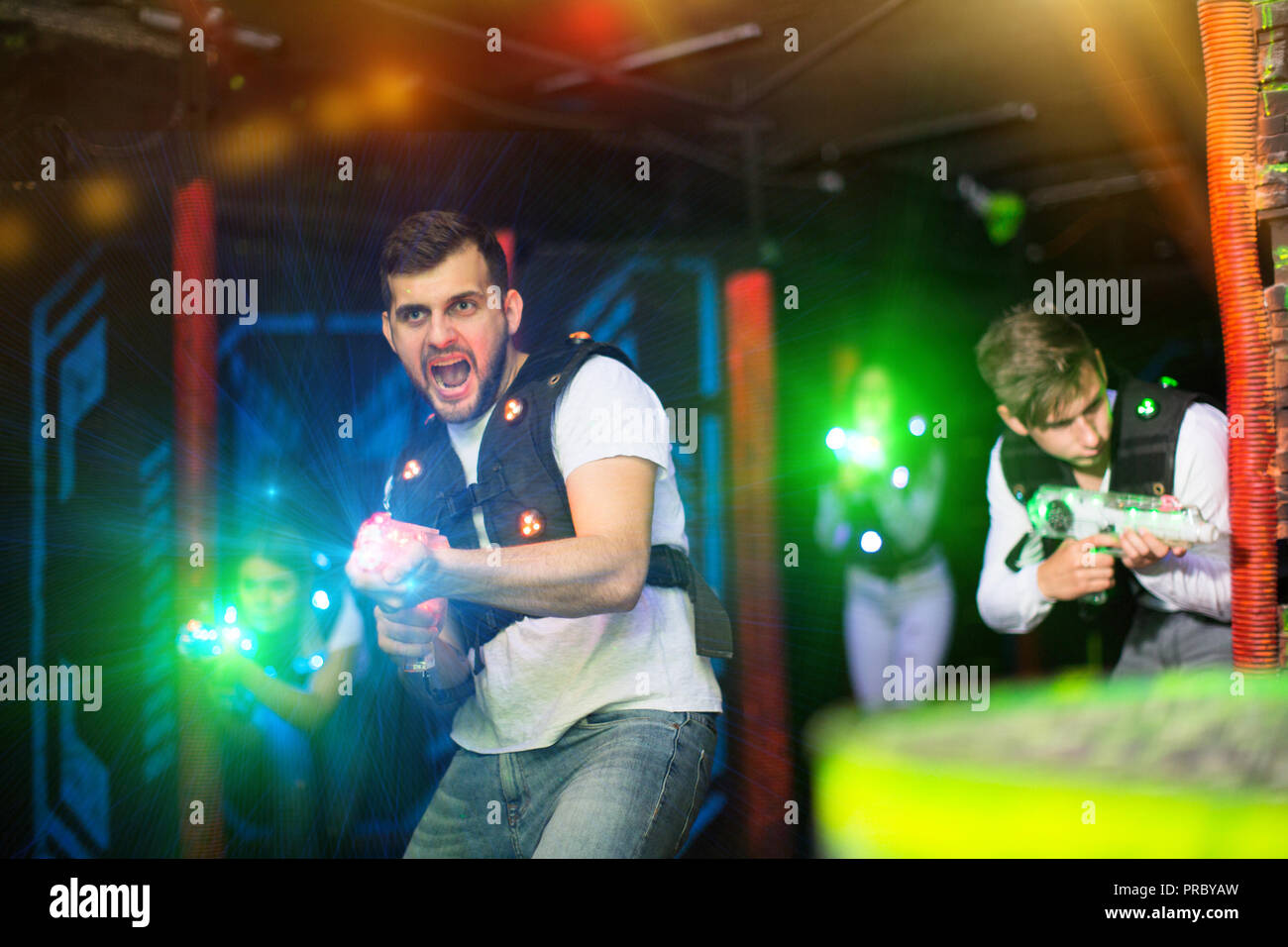 Portrait of guy in colored beams of laser guns during laser tag game on ...