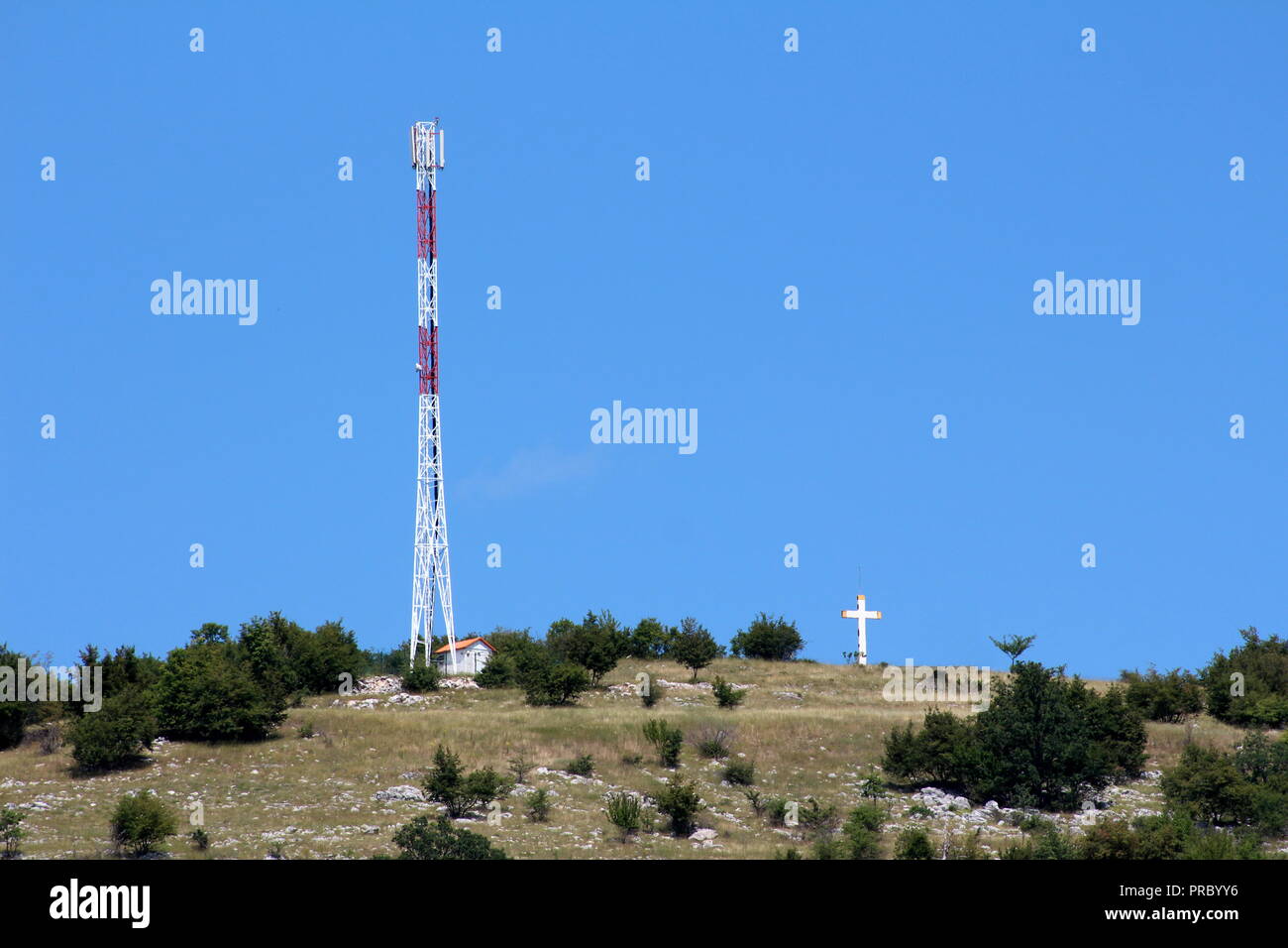 Tall cell phone red and white antenna tower with multiple antennas on top surrounded with strong ...