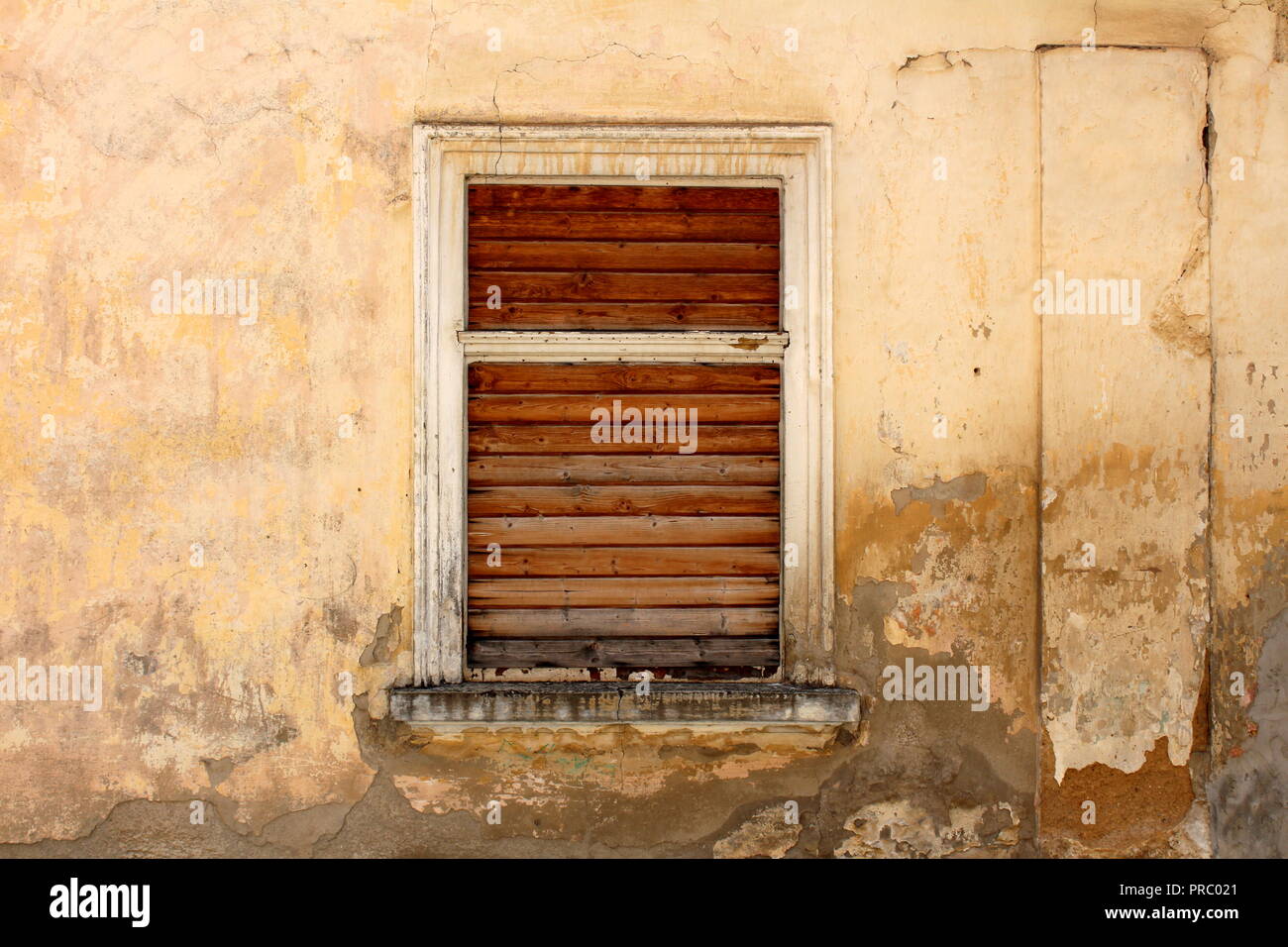 Wooden frame window with closed old wooden blinds on abandoned stone ...
