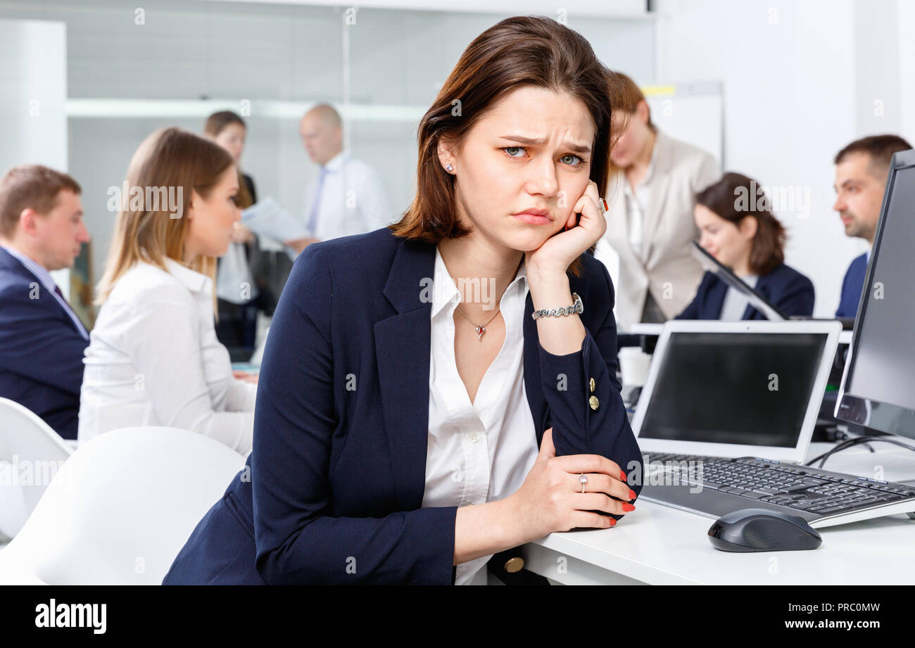 Portrait of angry unhappy girl in modern open plan office on background ...