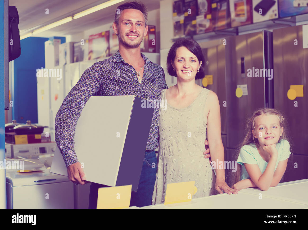 positive smiling family of three having new electronics in box in home ...