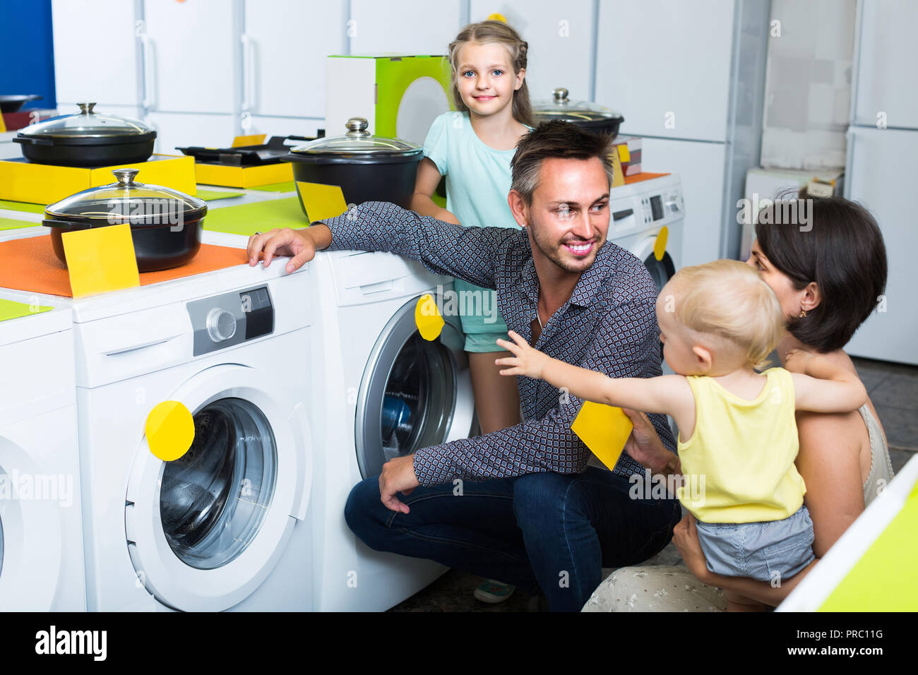 positive russian parents with two kids choosing washing machine in home ...
