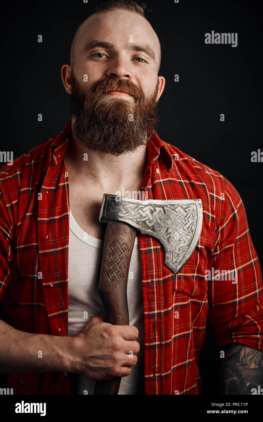 bearded male holding axe on chest and posing in studio Stock Photo - Alamy