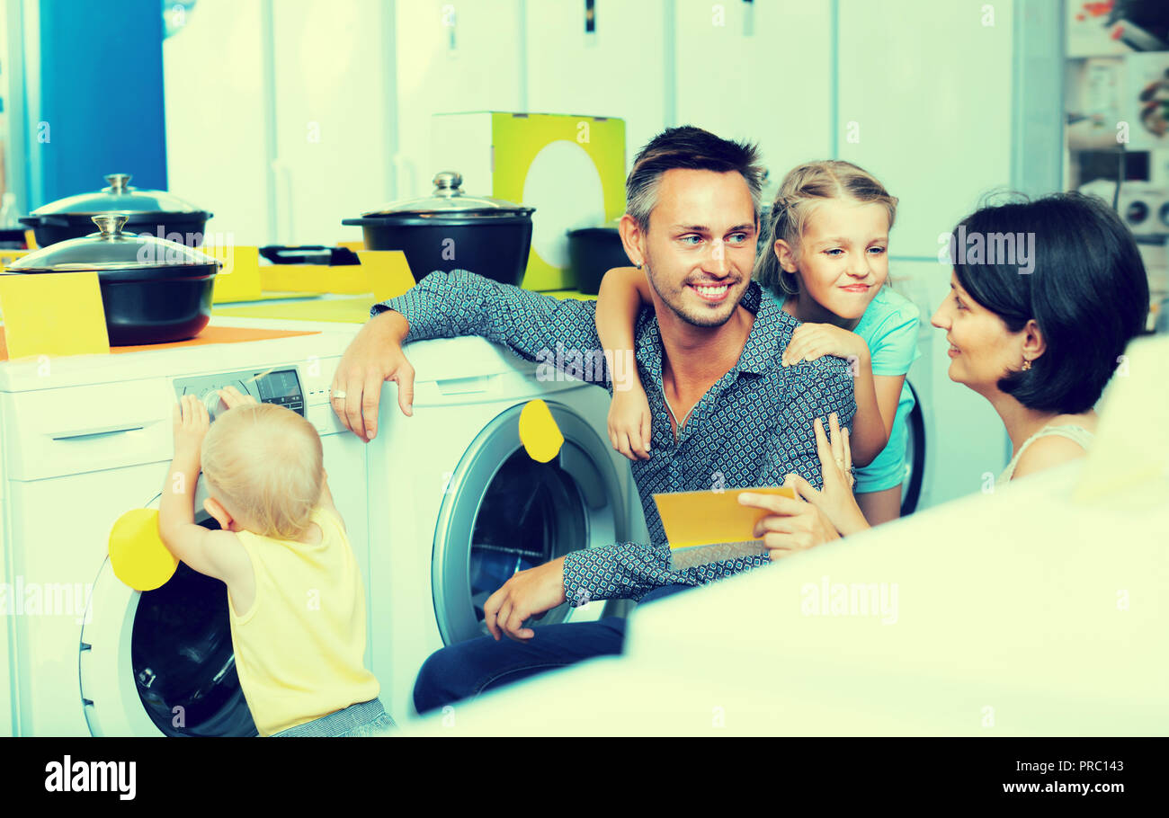 Happy family with two kids together choosing washing machine in shop of ...