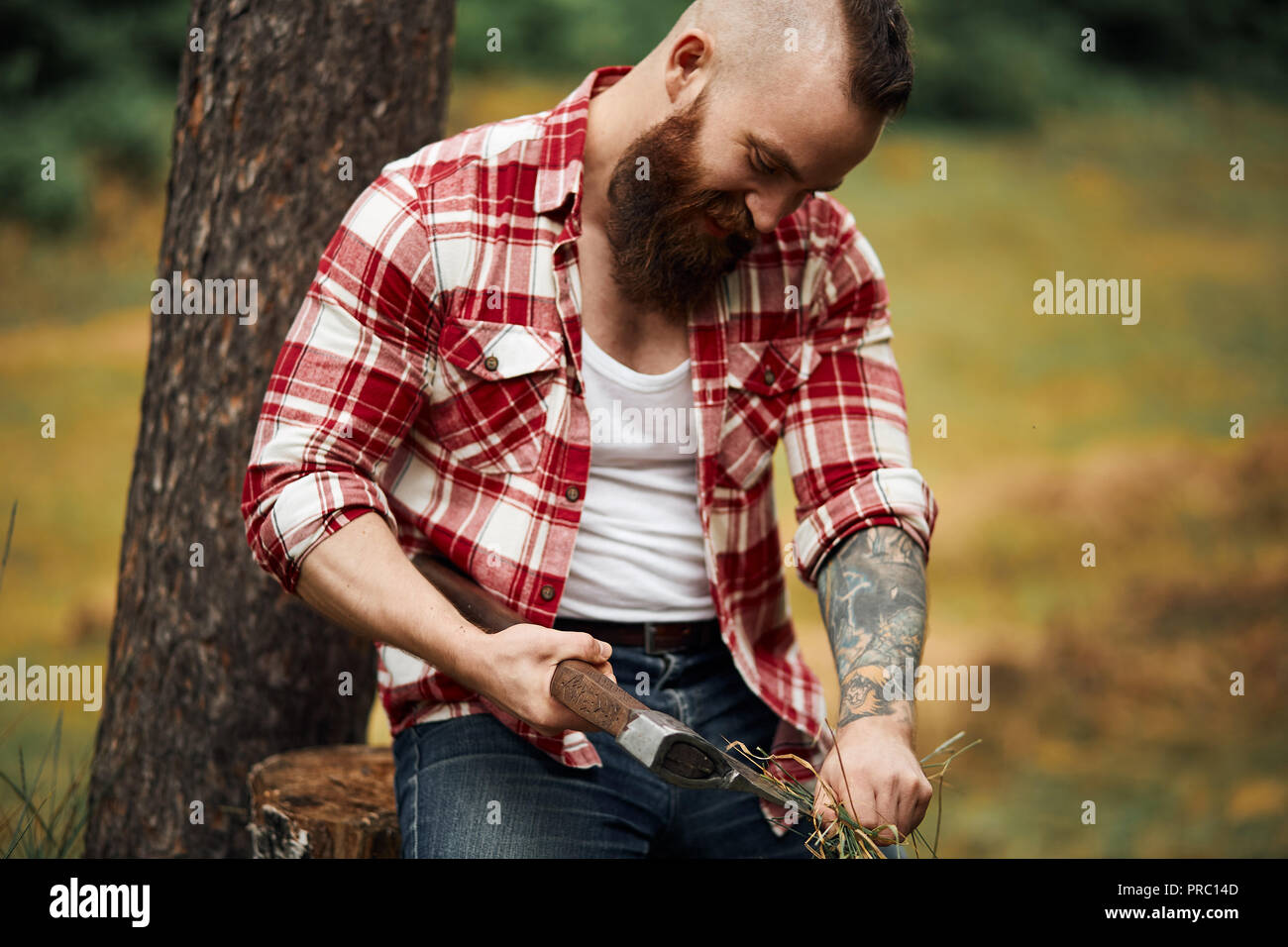 bearded man wipes clean axe with leaves. Bearded axeman Stock Photo - Alamy