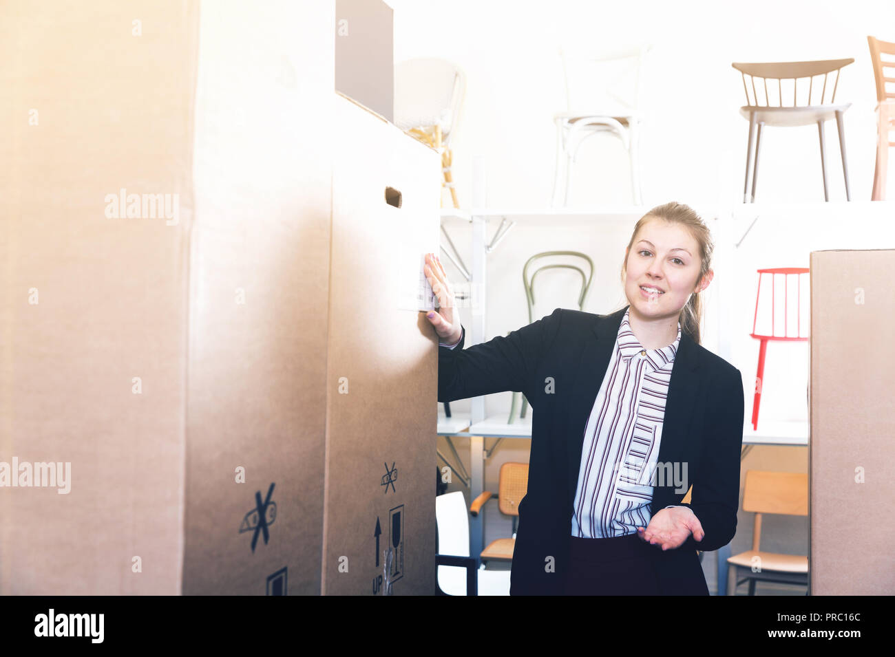 Portrait of successful female owner of chair store standing among ...