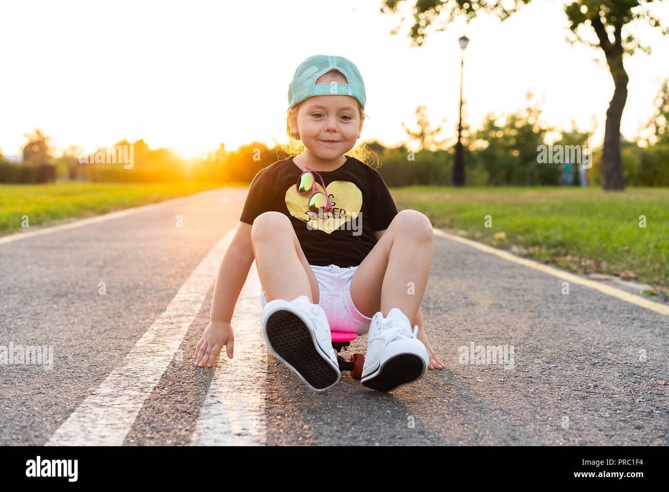 Child riding skateboard in summer park. Little girl learning to ride ...