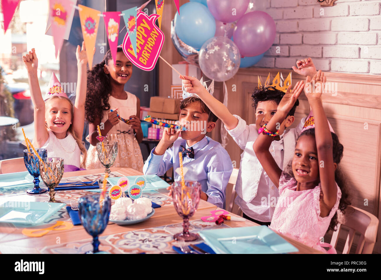 Kids having fun and putting hands up while being at birthday party ...