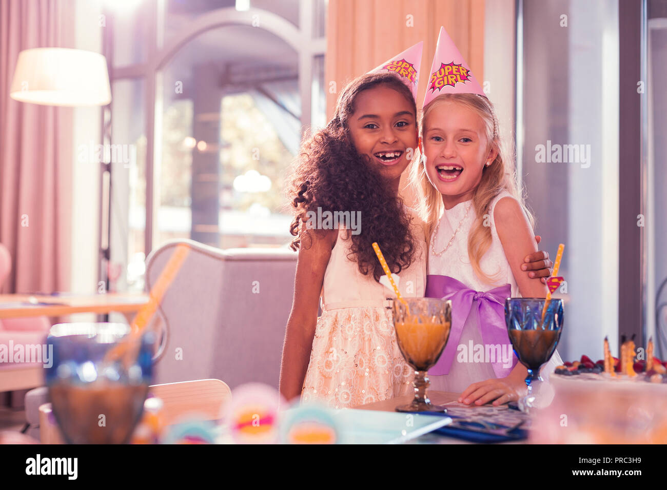 Two girls laughing while standing next to the table Stock Photo - Alamy