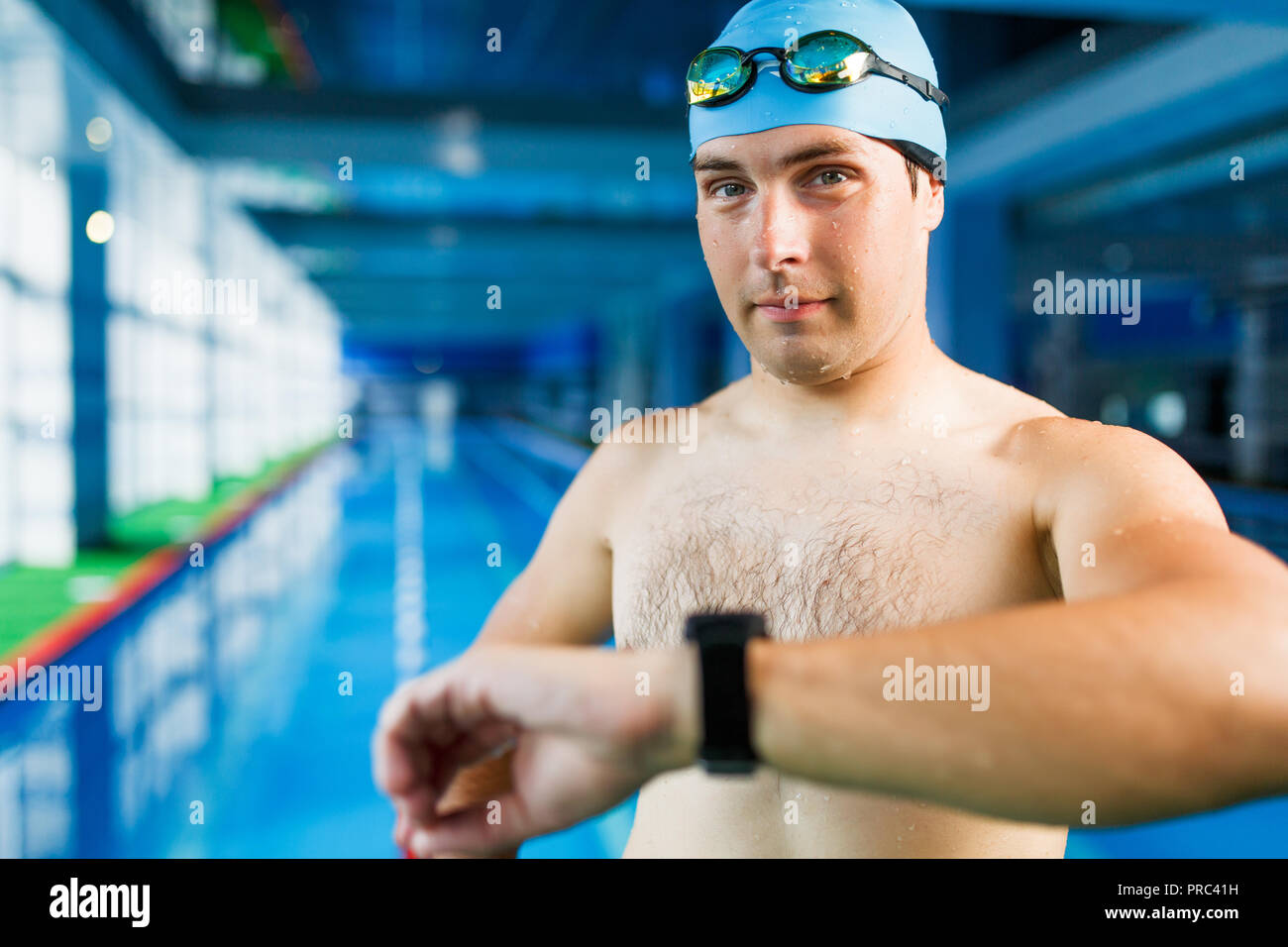 Photo of swimmer man with timer on arm standing in pool during workout ...