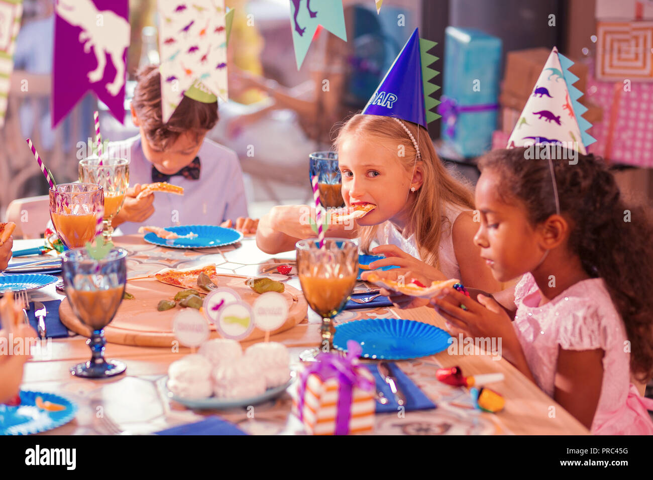 Three children sitting silently while eating tasty food Stock Photo - Alamy