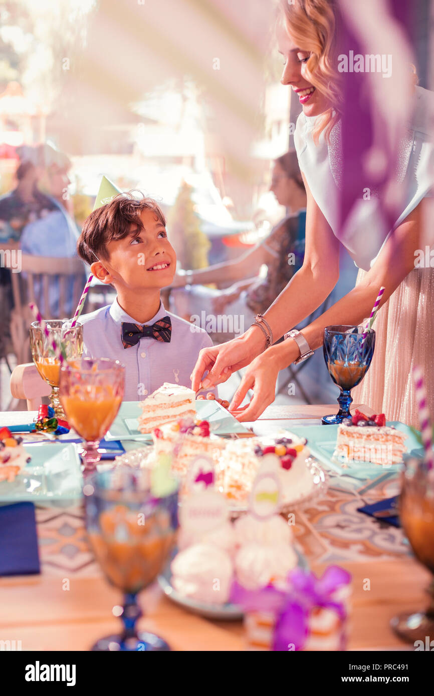 Adorable boy looking at his mother giving cake to all children Stock ...