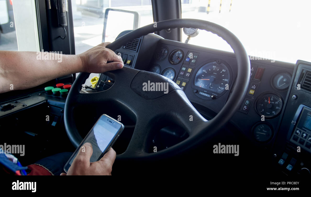 Closeup image of bus driver using smartphone while driving. Danger in ...