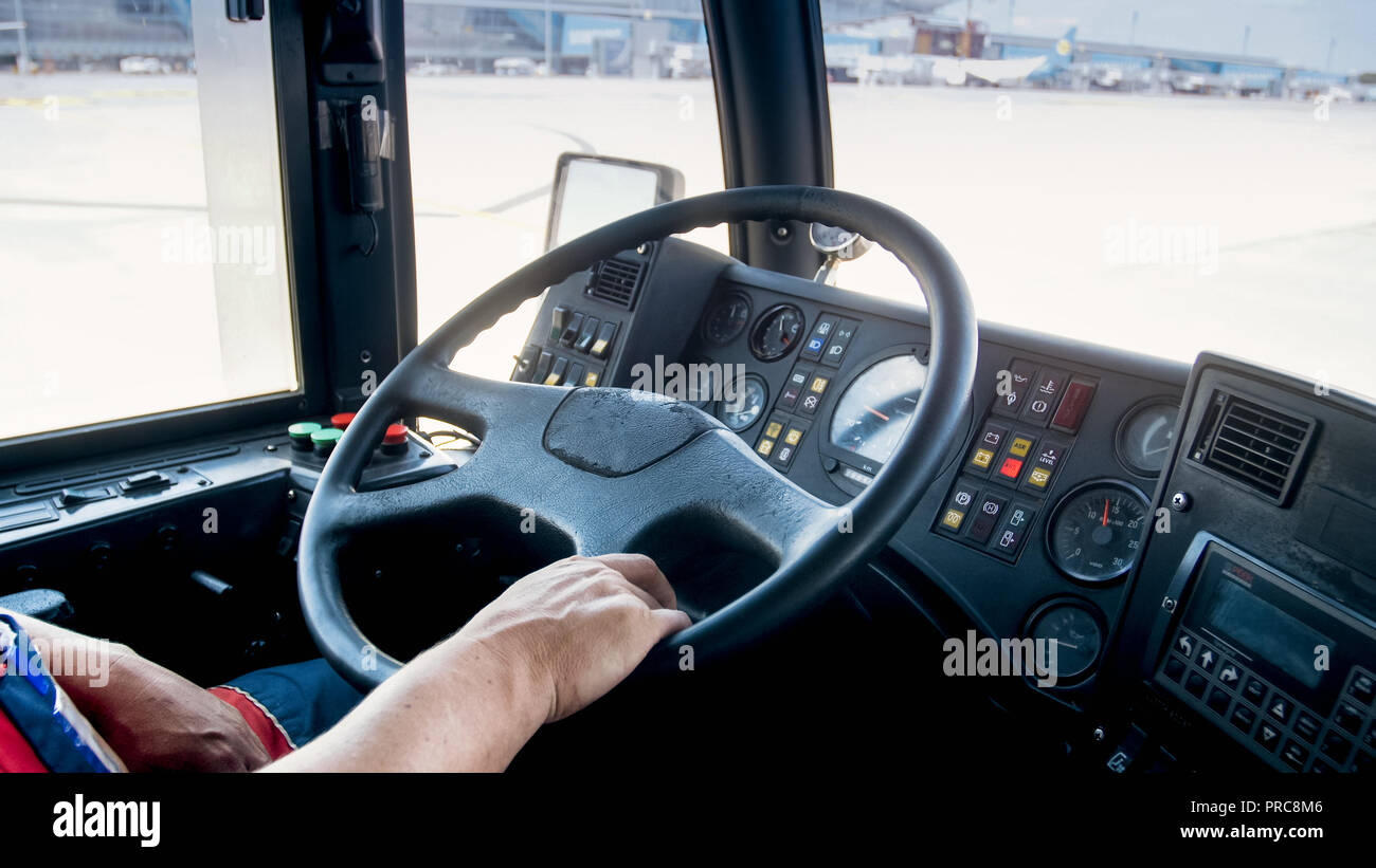 Closeup image of man driving bus with passenger towards airplane on ...