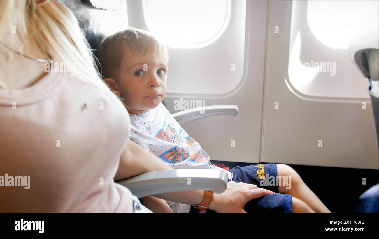 Little boy scared of first flight in airplane looking at mother Stock ...